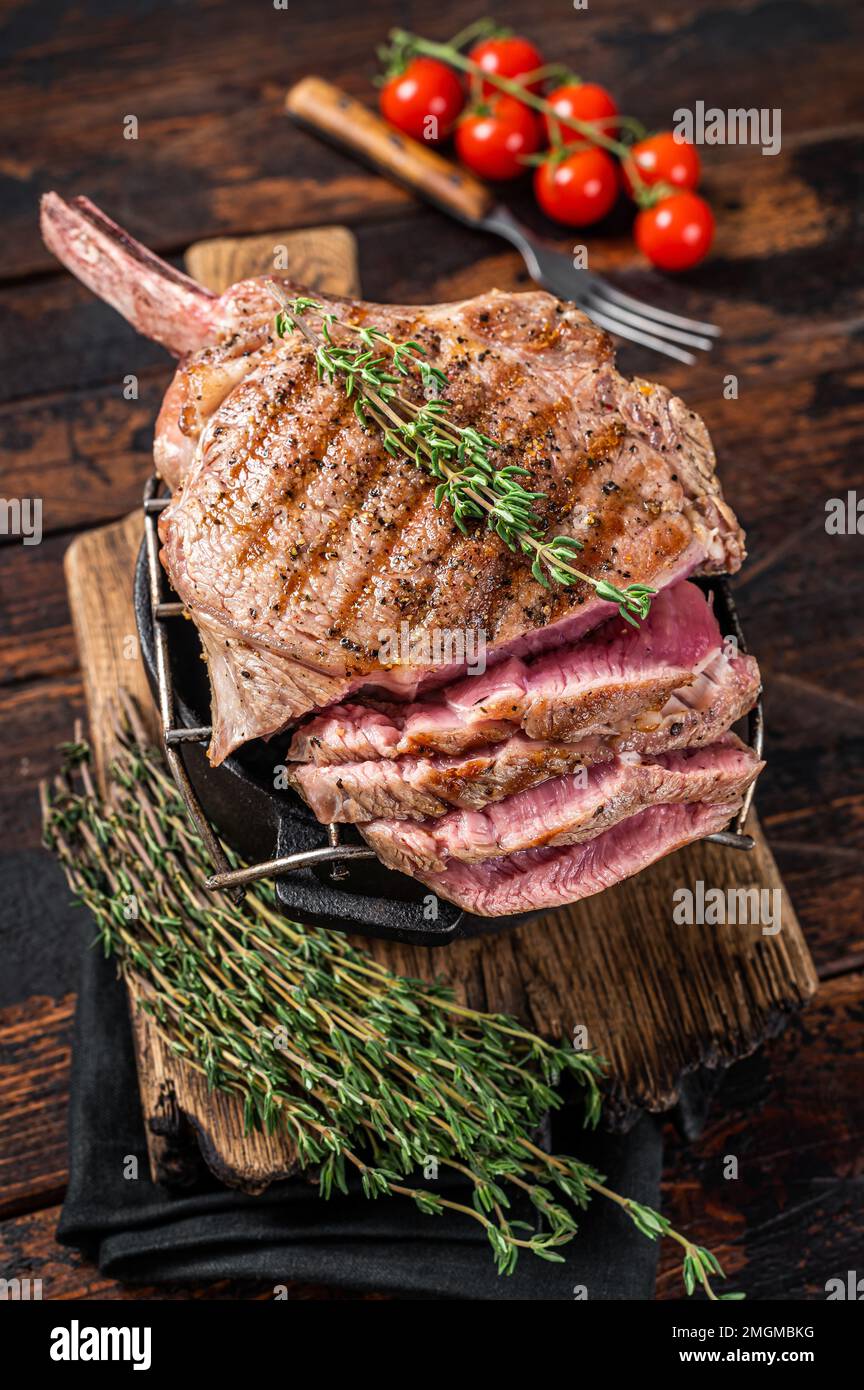 Grilled Tomahawk rib eye steak on grill with herbs. Wooden background ...