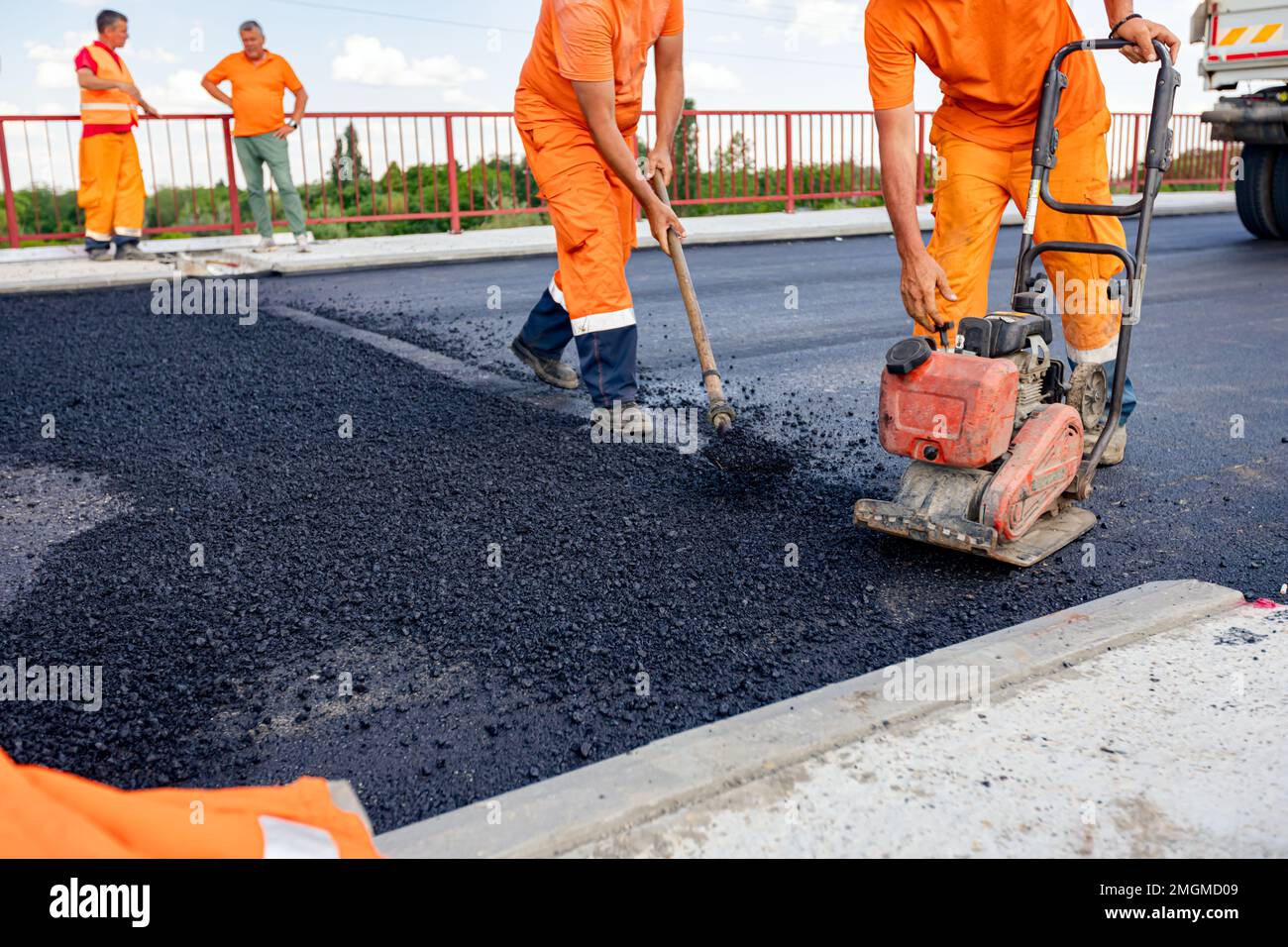 Worker is compacting asphalt with vibrating compactor machine, the ...
