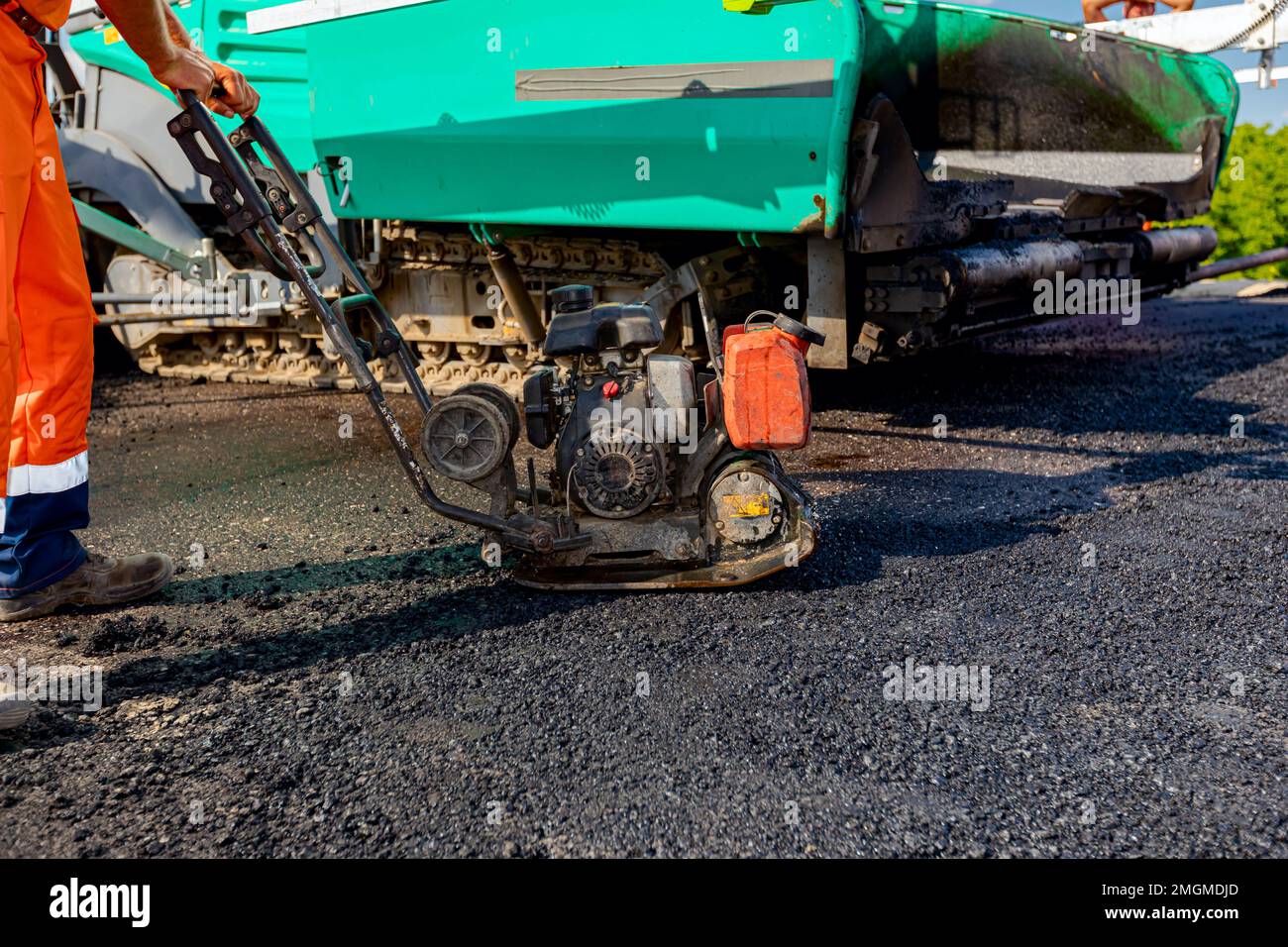 View on worker who is compacting asphalt with vibration plate ...