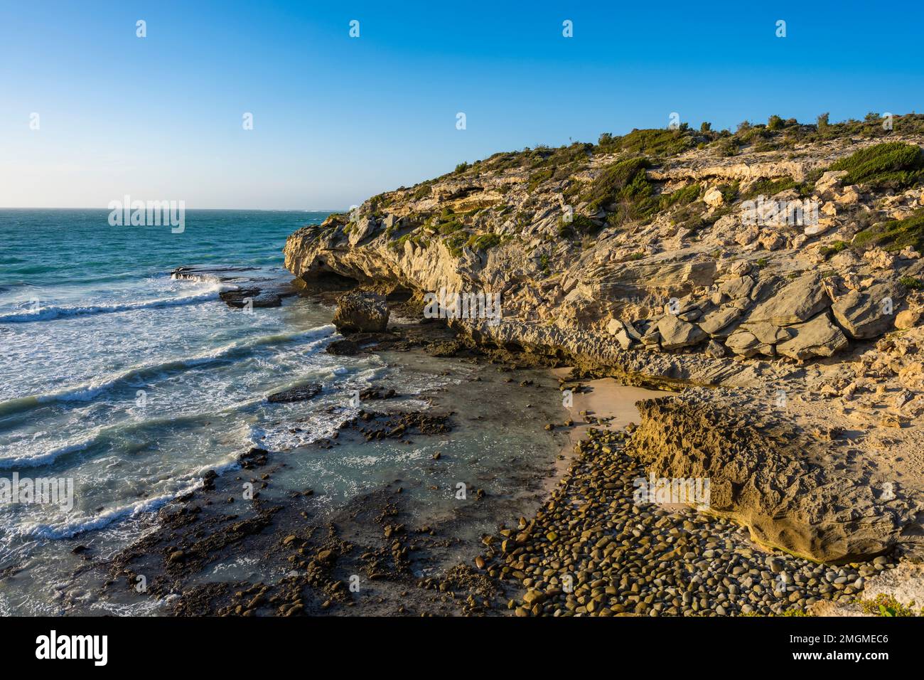 An exterior view of Waenhuiskrans sea-cave and the rocky shoreline ...