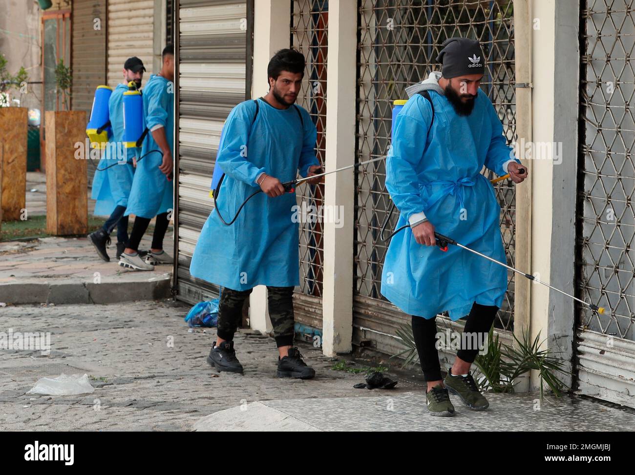 Iraqi volunteers spray disinfectant as a precaution against the ...