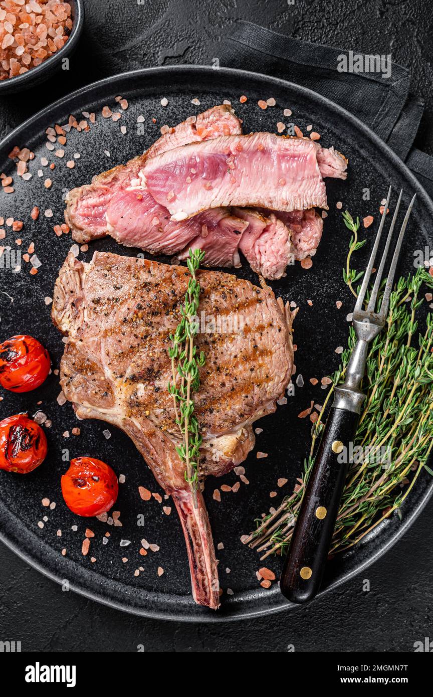Barbecue sliced rib eye Tomahawk beef (veal) steak on a plate with pink ...