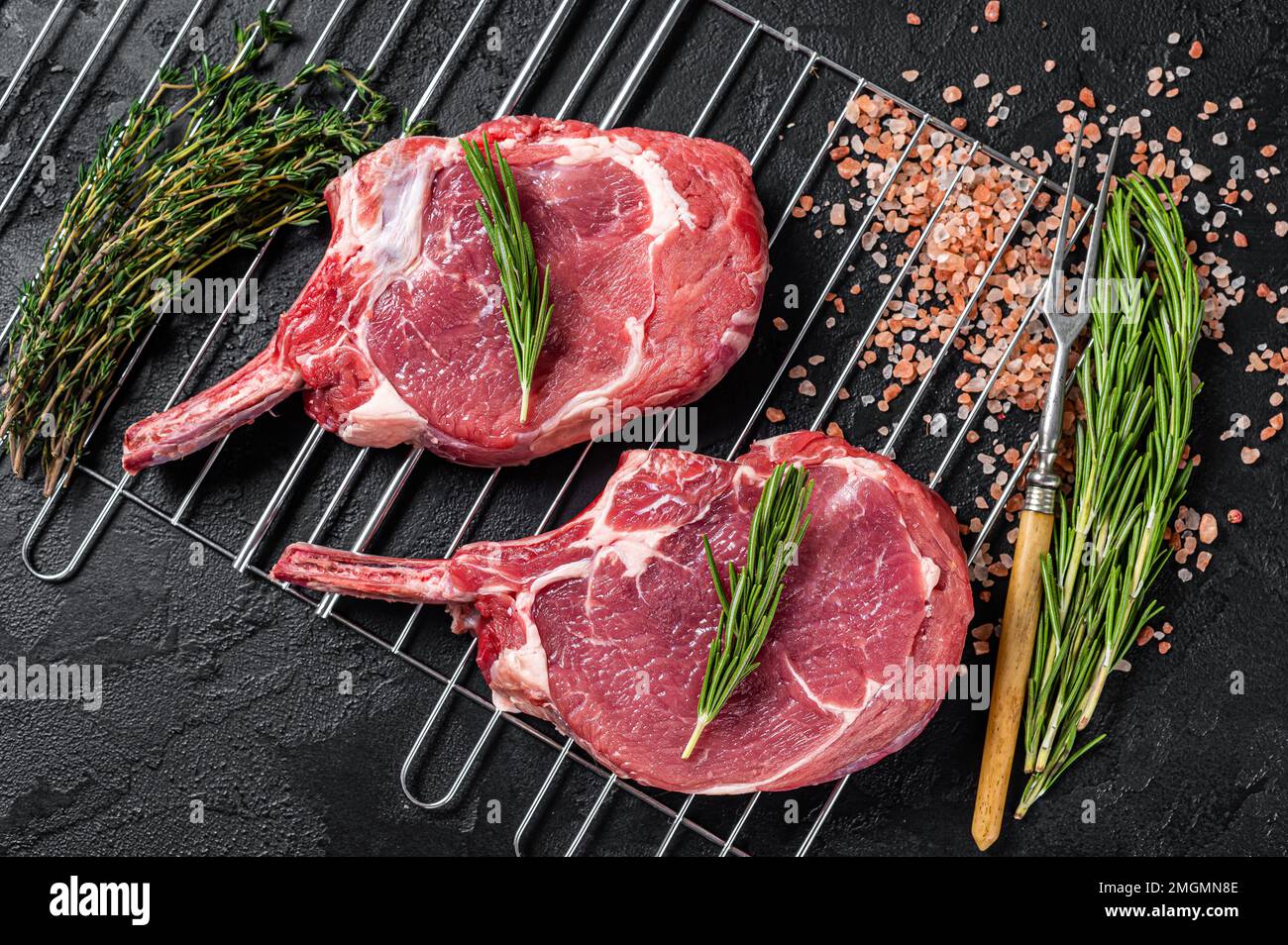 Fresh Raw Tomahawk rib eye beef steaks on grill. Black background. Top ...