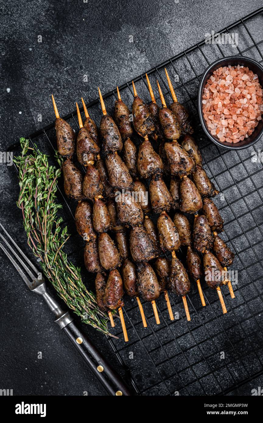 Grilled shish kebab with chicken hearts on a grill. Black background ...