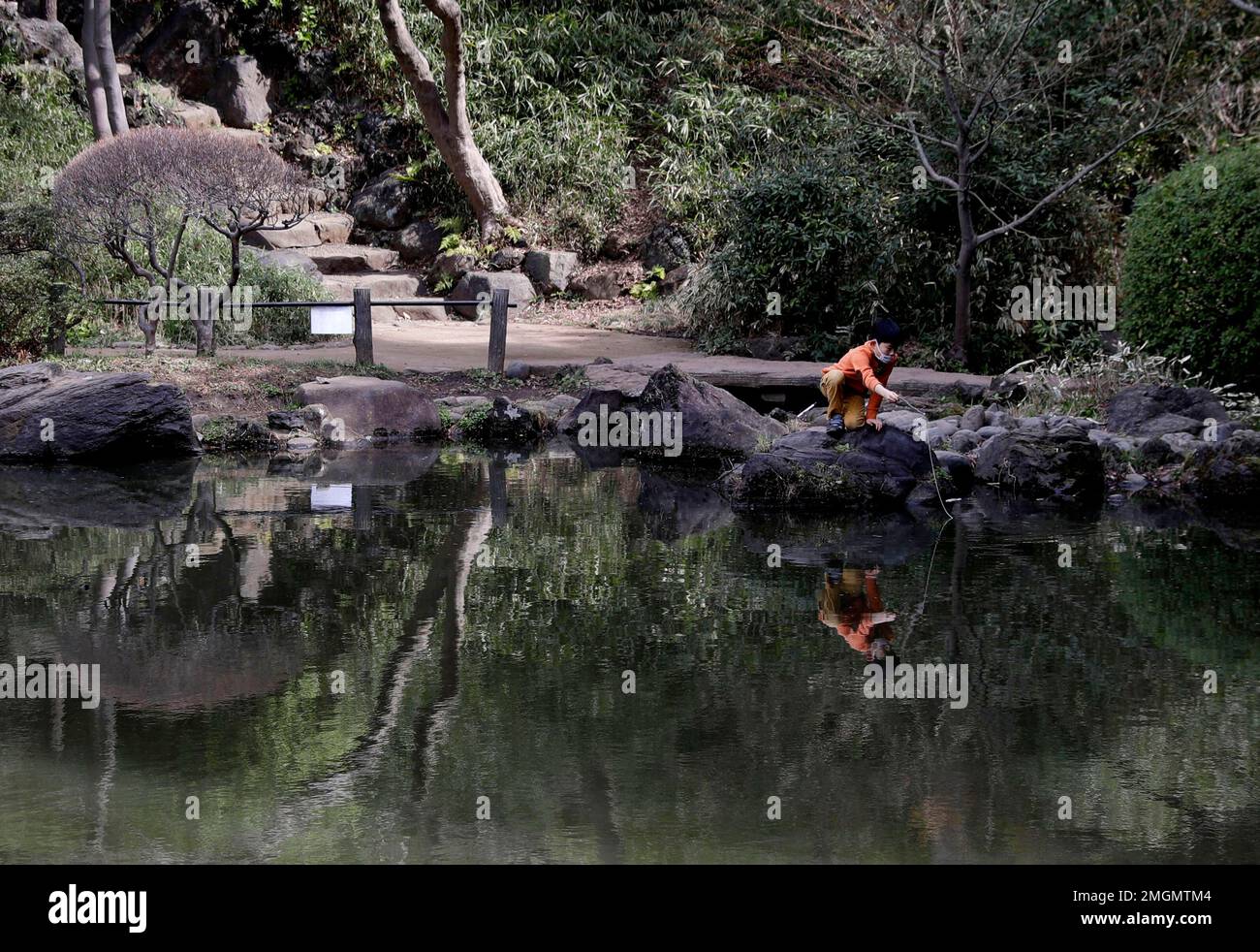 A child casts his makeshift fishing line into the lake of the Arisugawa ...