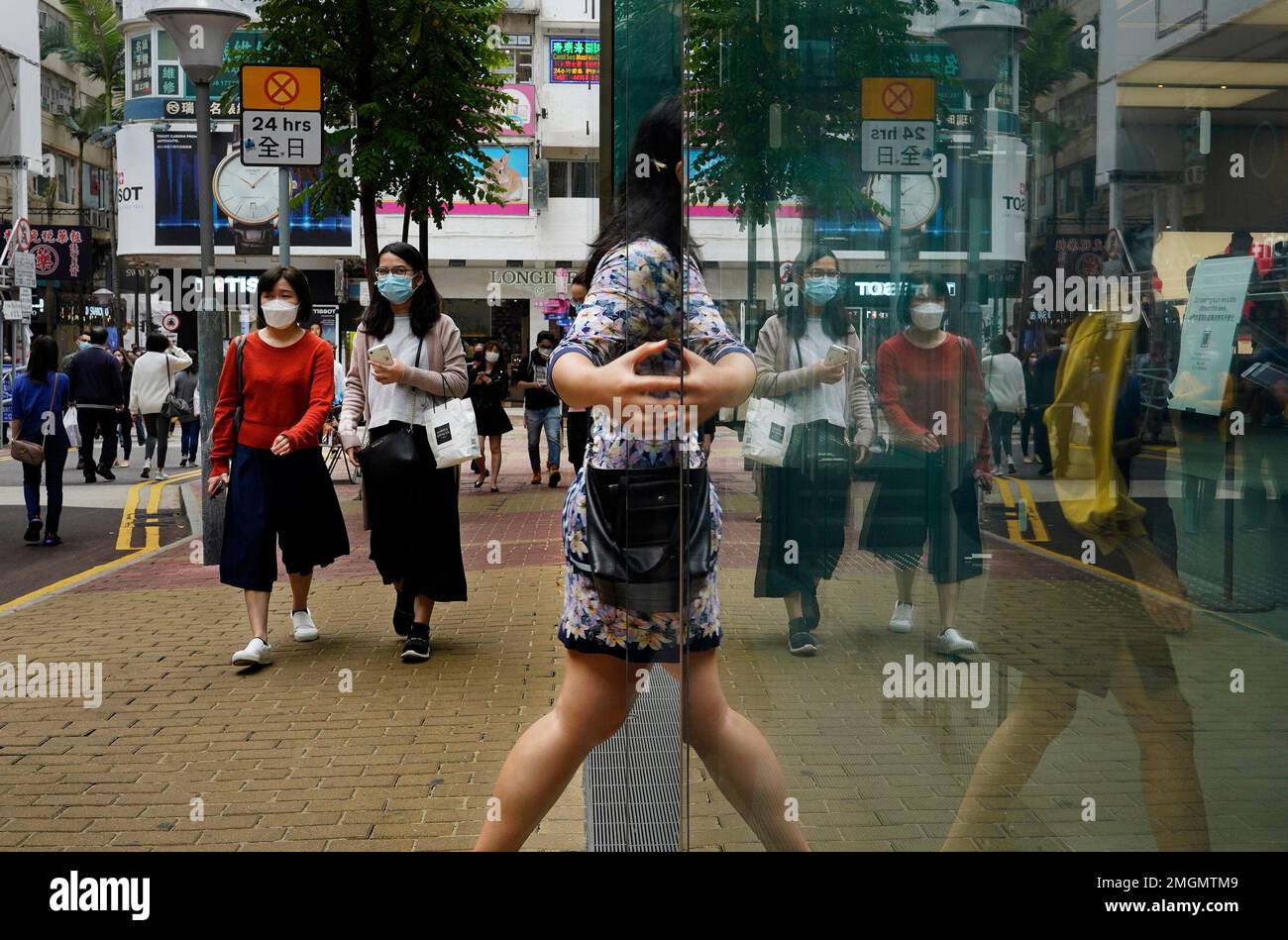 People wearing face masks walk on a street in Hong Kong Friday, March ...