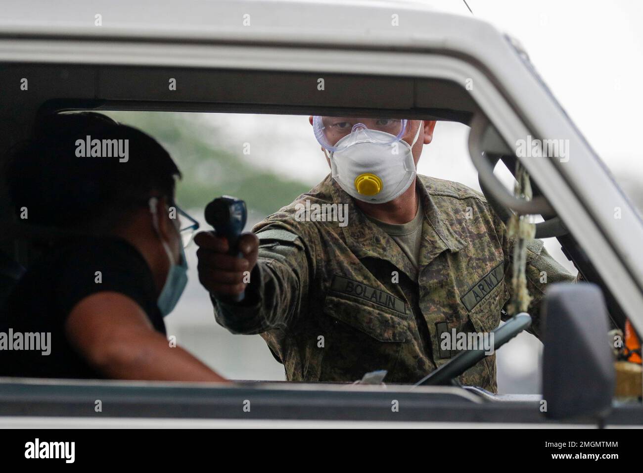 An army trooper uses a thermal scanner to check the temperature of ...