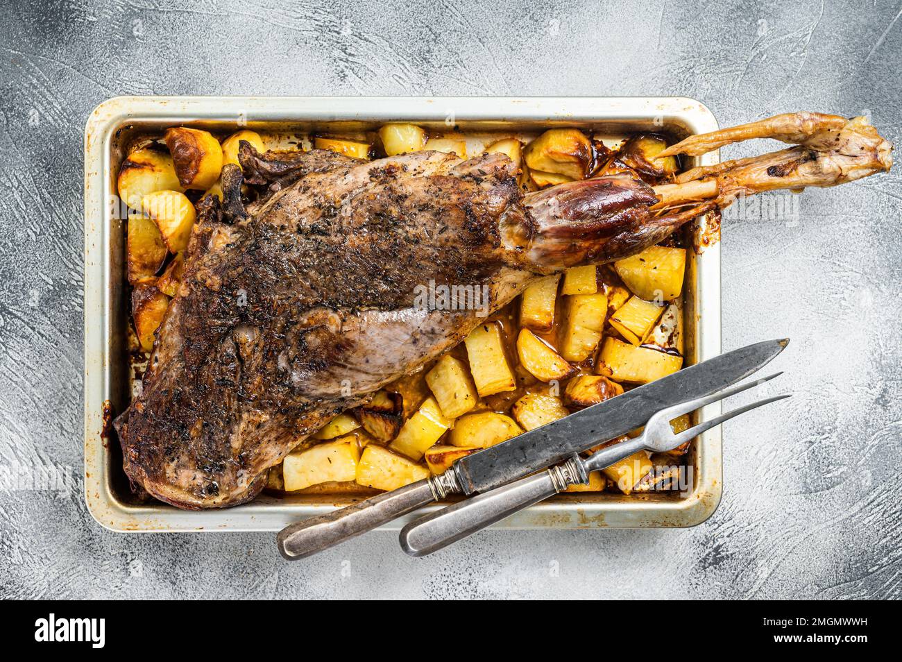 Roast lamb mutton leg with potatoes and rosemary in baking dish. White ...