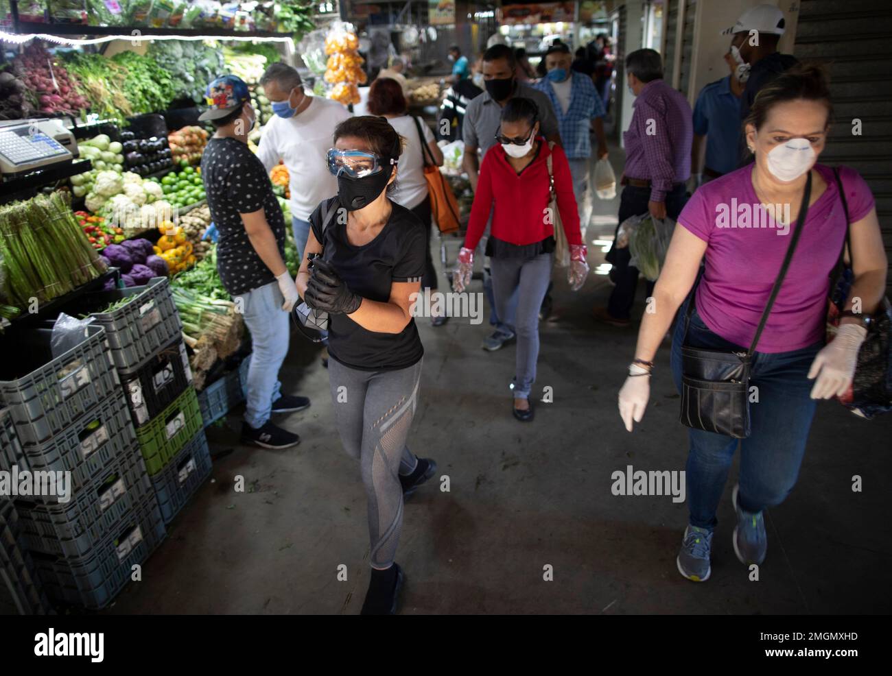 Shoppers and vendors wear protective items like face masks, goggles and ...