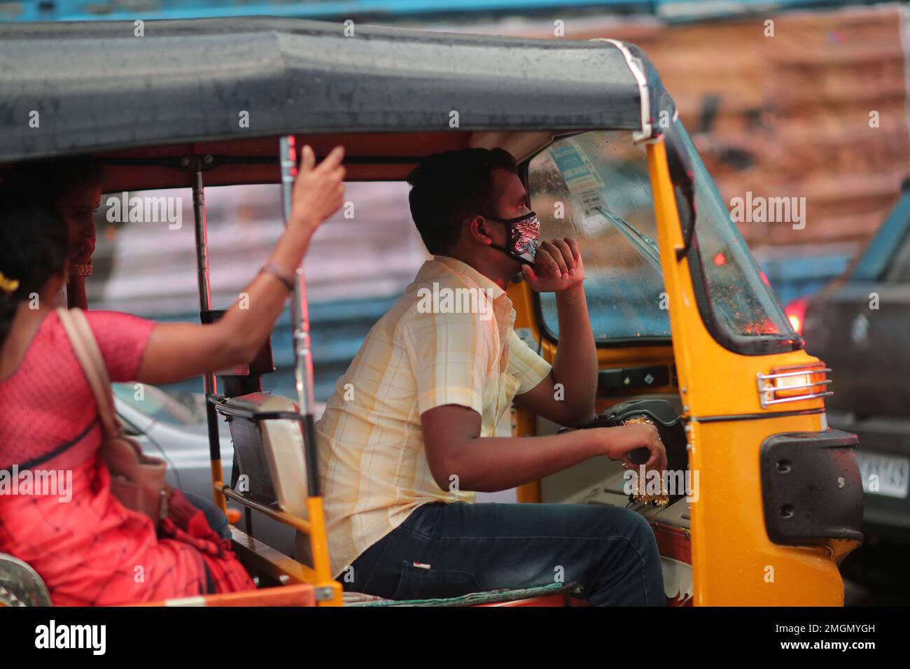 An Indian auto rickshaw driver wears a face mask as a precaution ...