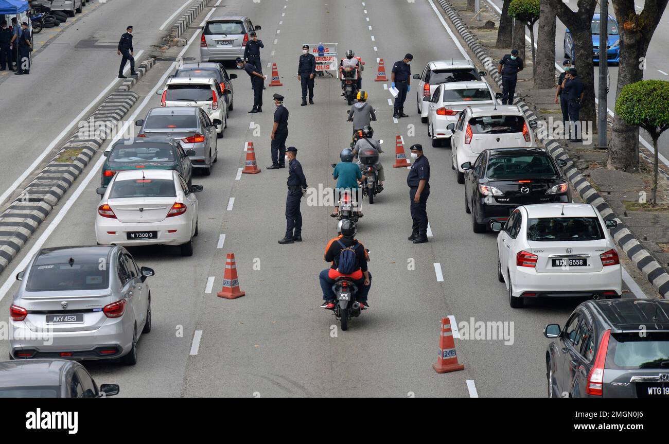 Police officers check vehicles at roadblock to ensure that people abide ...