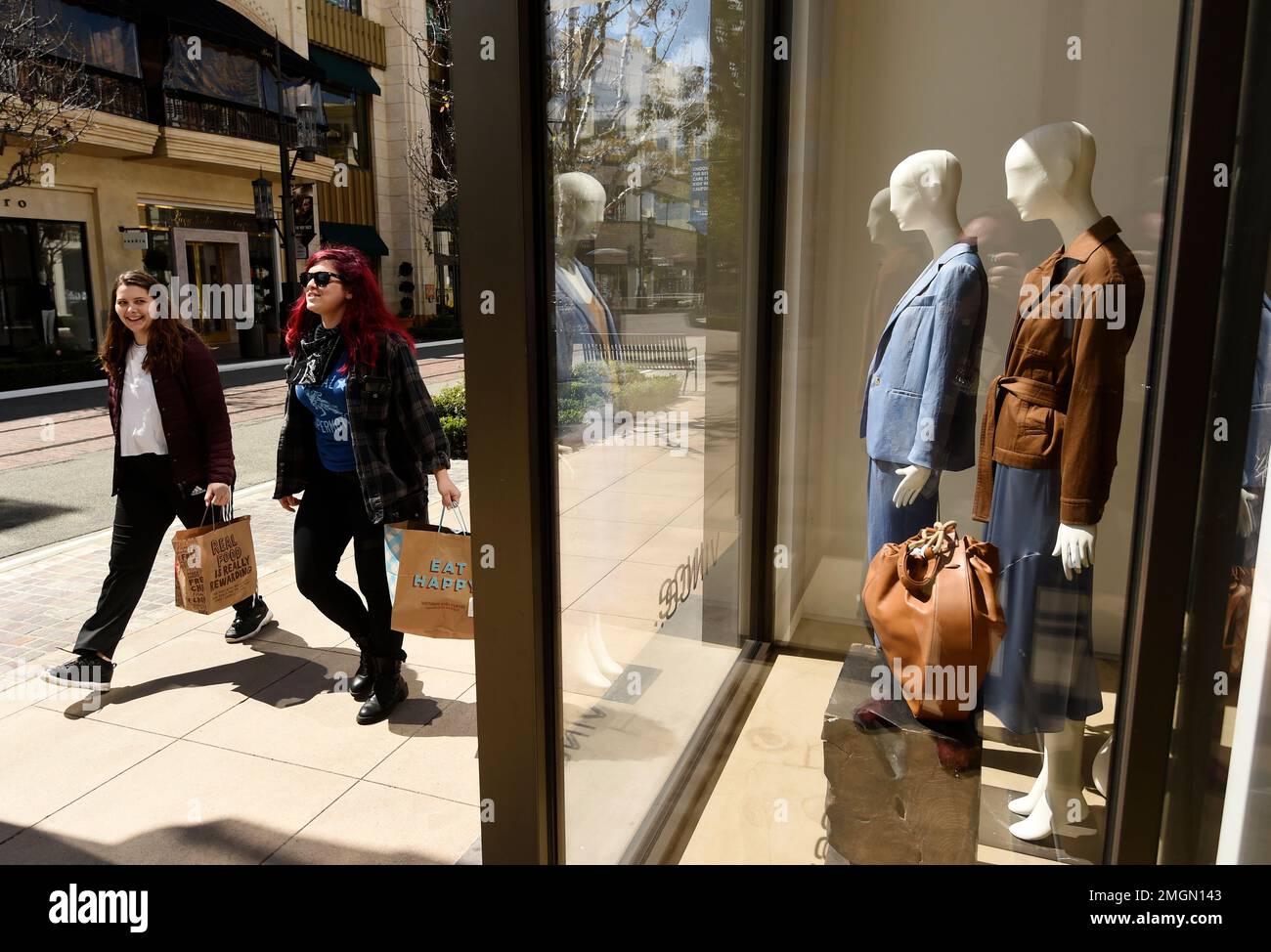 Pedestrians walk past the display window of the Vince clothing store at ...