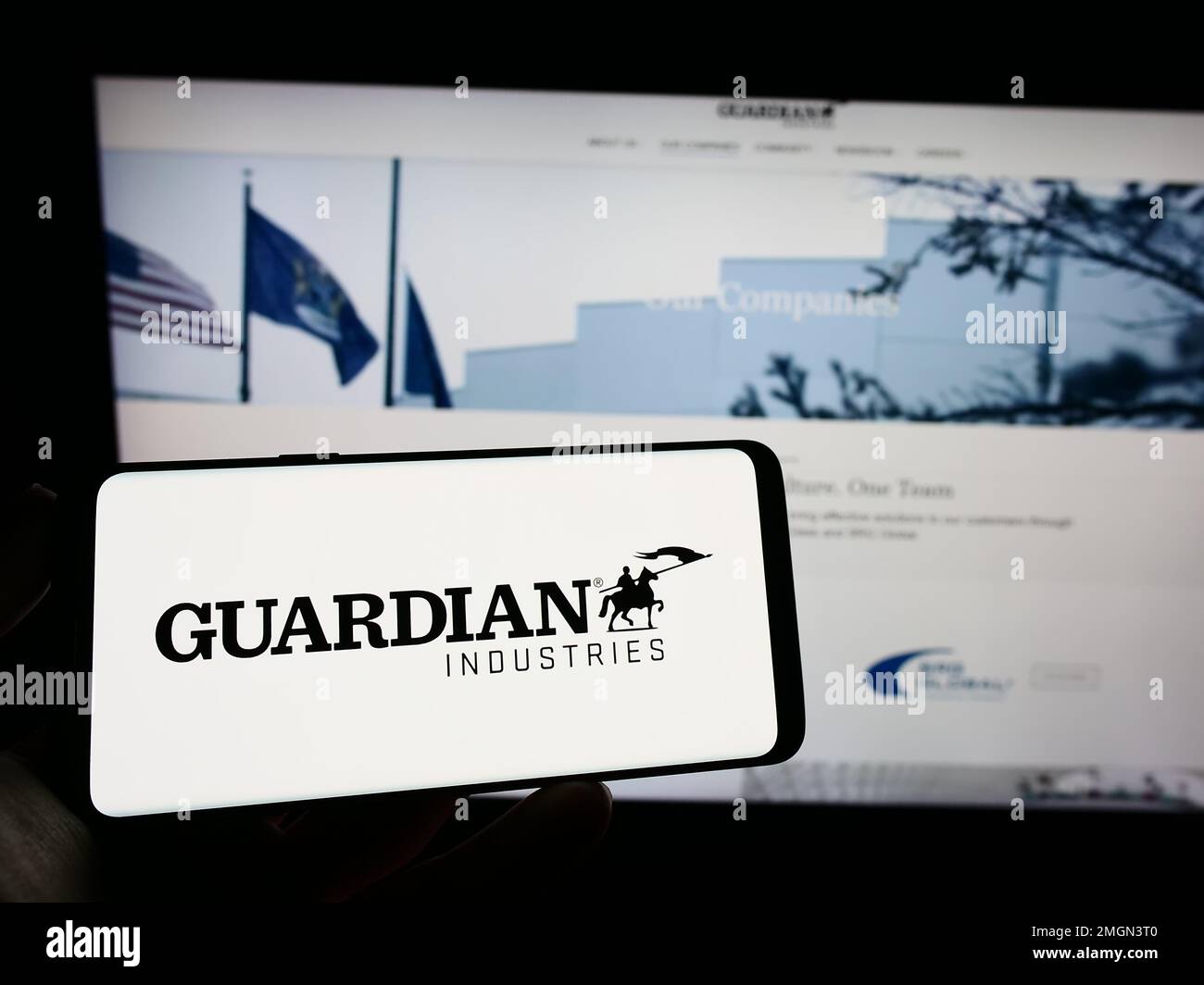 Person holding mobile phone with logo of US glass producing company ...