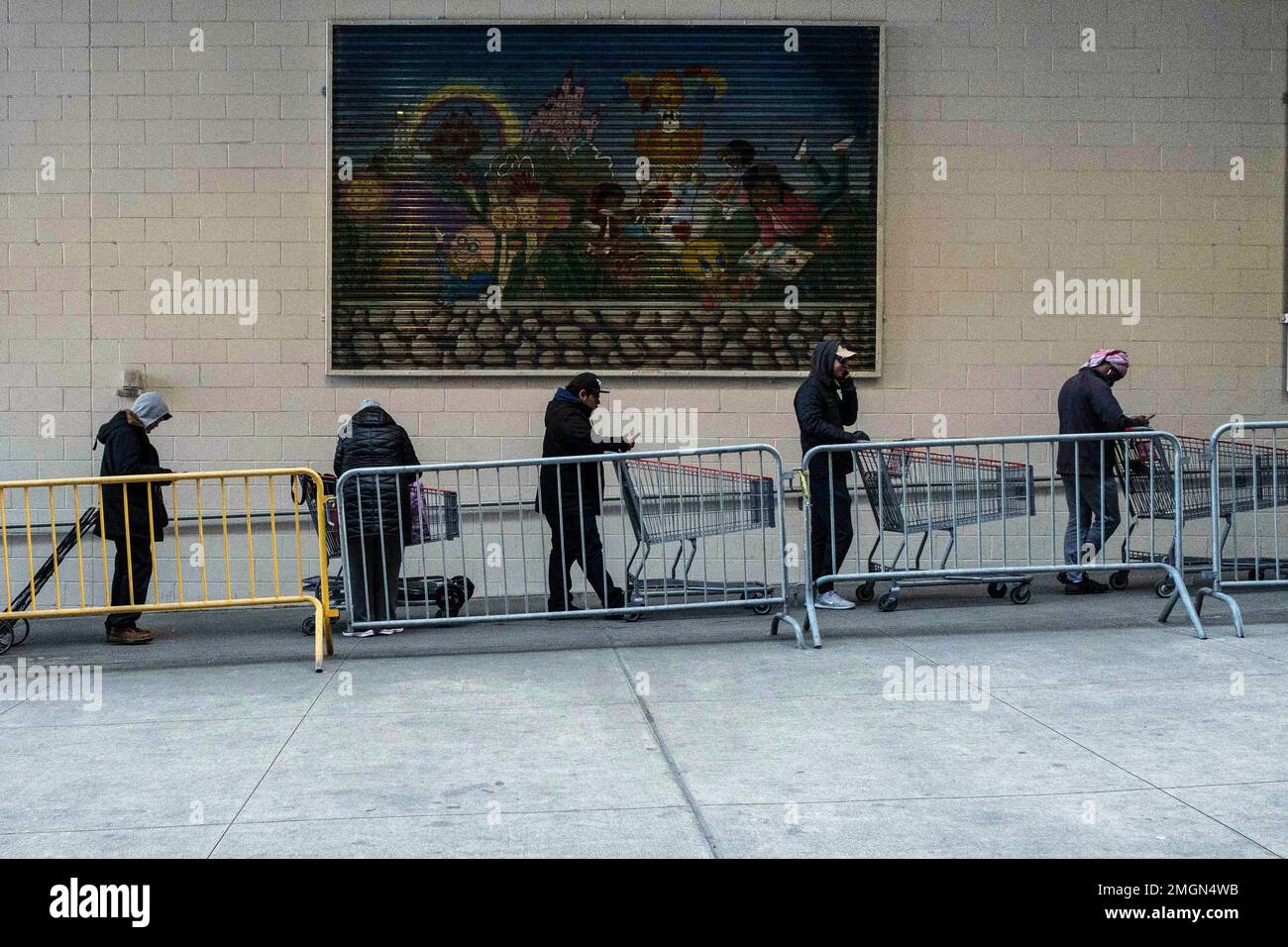 Customers make a line with shopping carts at a local retail store ...