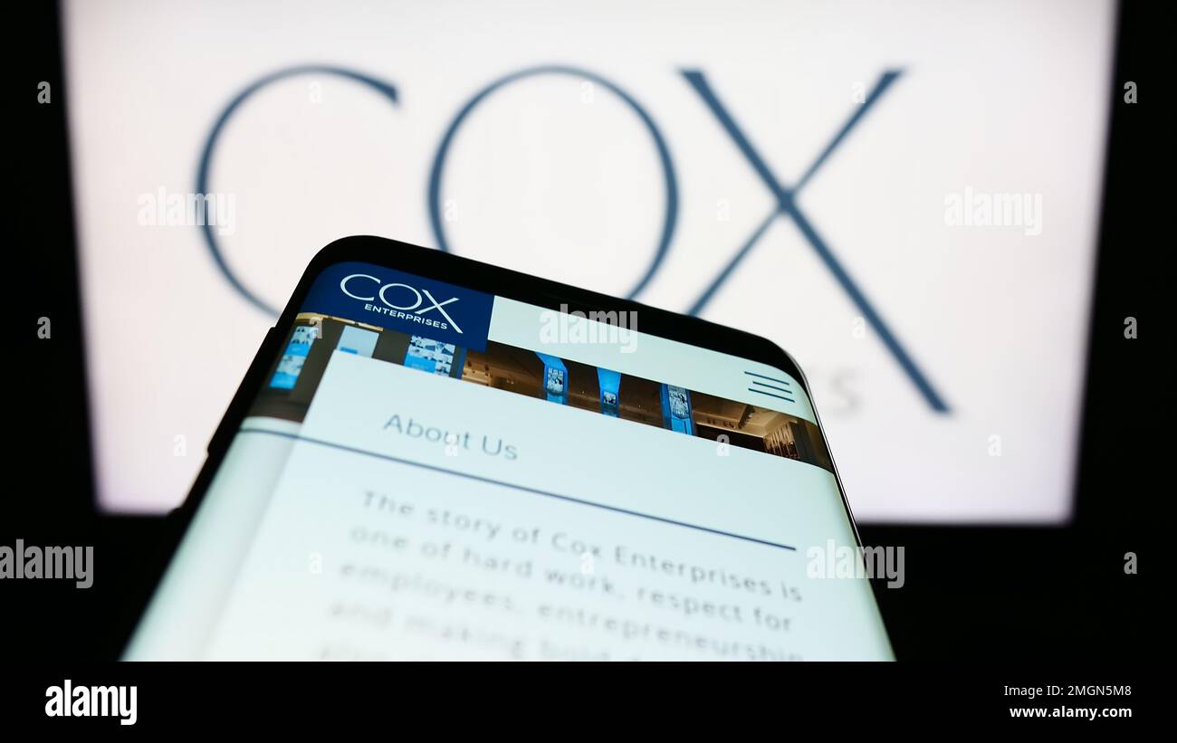 Mobile phone with website of US company Cox Enterprises Inc. on screen ...