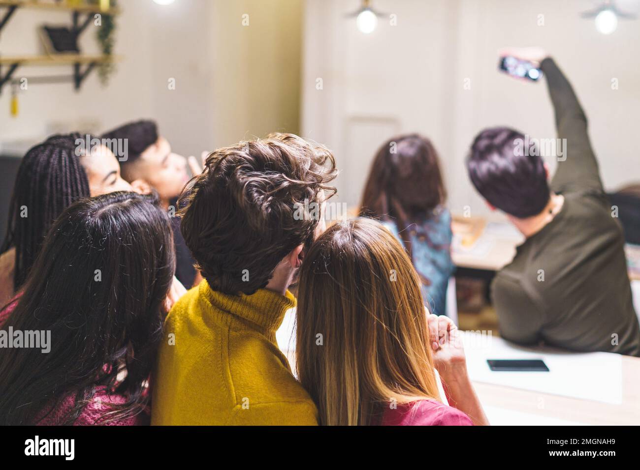 A group of diverse, multicultural friends gather in the kitchen for a ...
