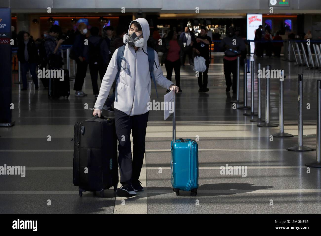 A masked traveler walks with luggage at the Los Angeles International ...