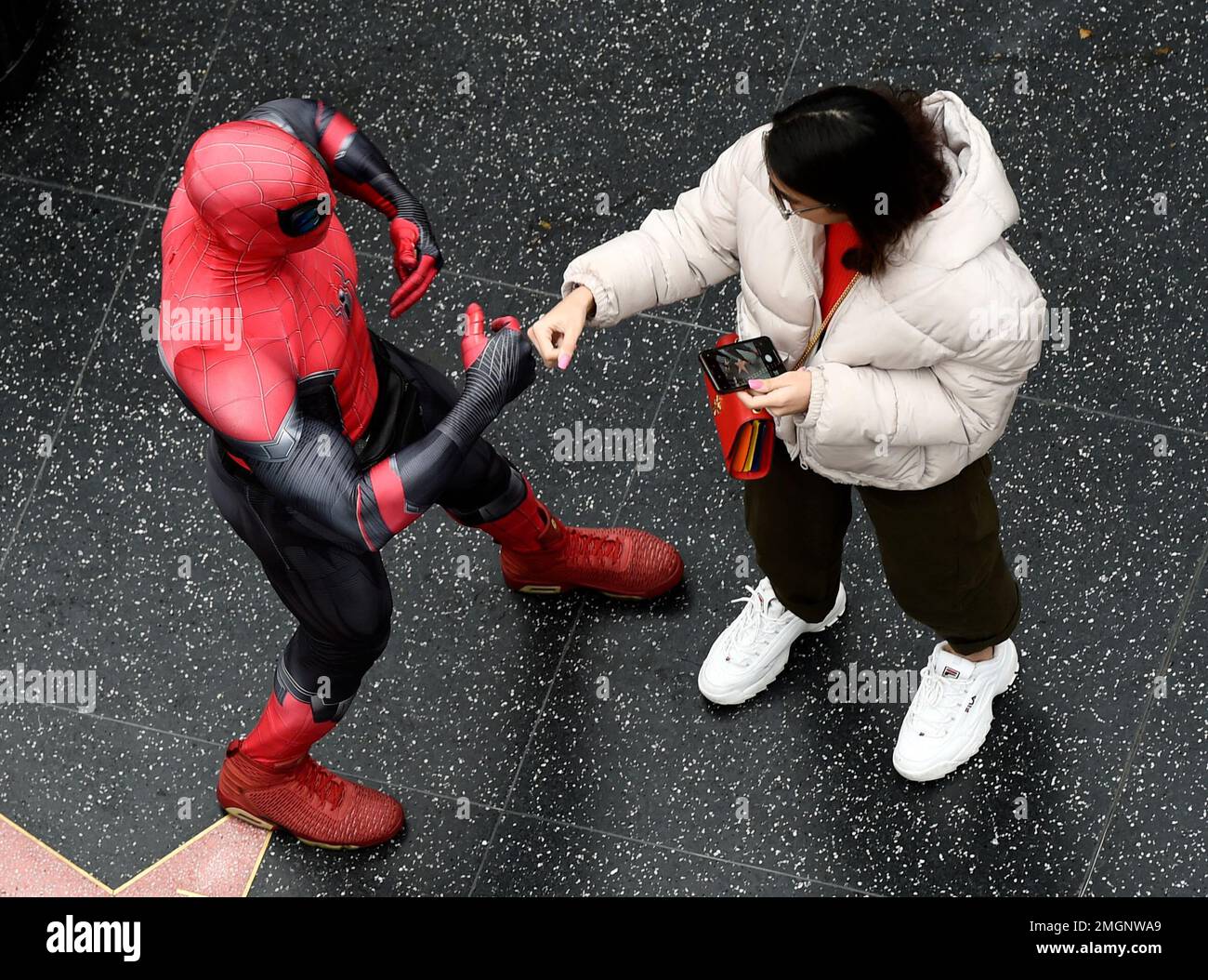 A Spider-Man costume character fist bumps a pedestrian on Hollywood ...