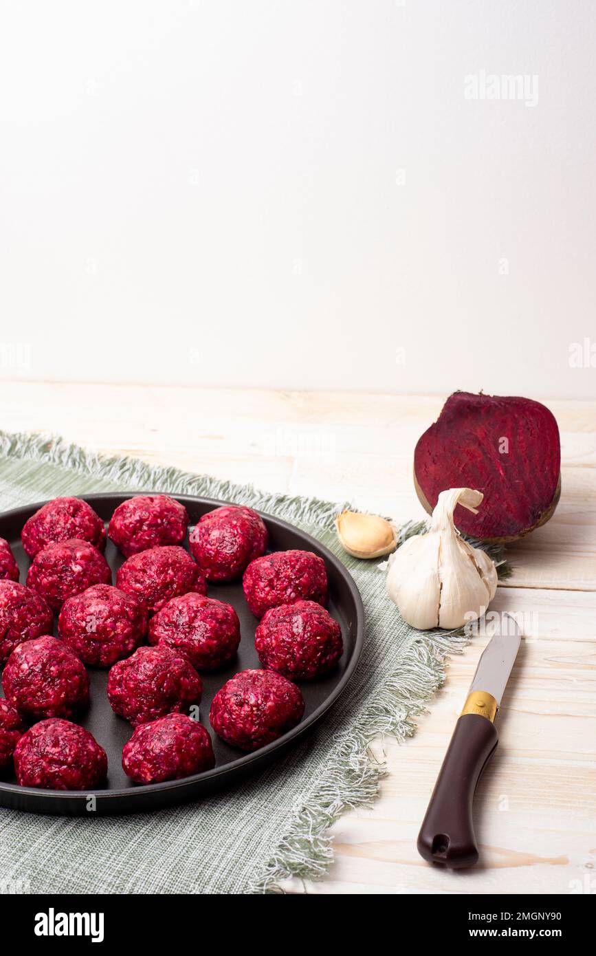Raw meatballs with beetroot into a black baking tray Stock Photo - Alamy
