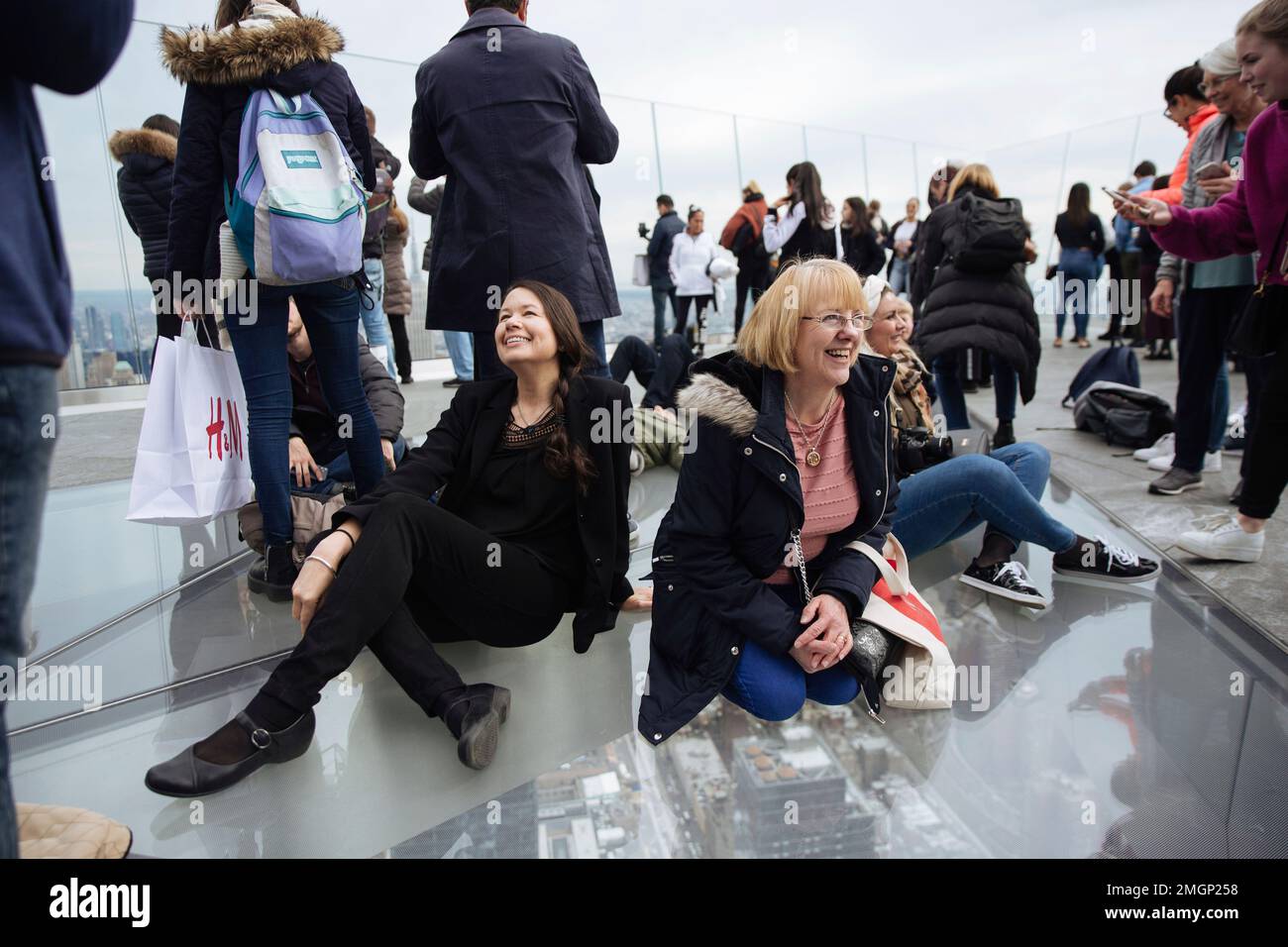 Tourists sit on the glass floor at Edge, the new observation deck on ...