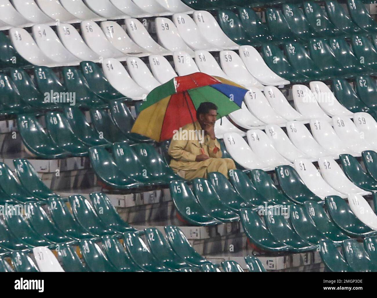 A spectator at Gaddafi Stadium sits alone in the stands with an ...