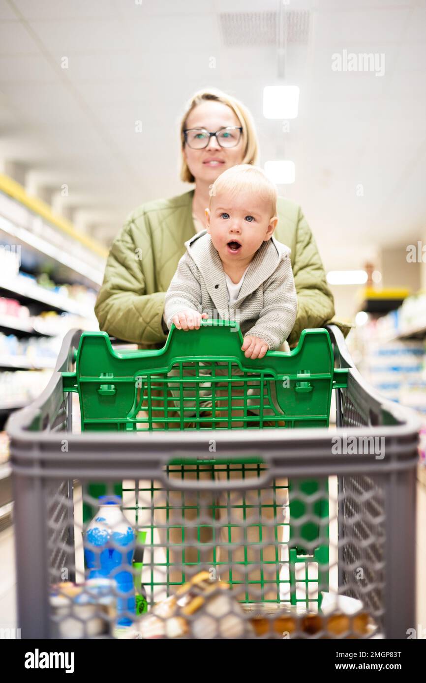 Mother pushing shopping cart with her infant baby boy child down ...