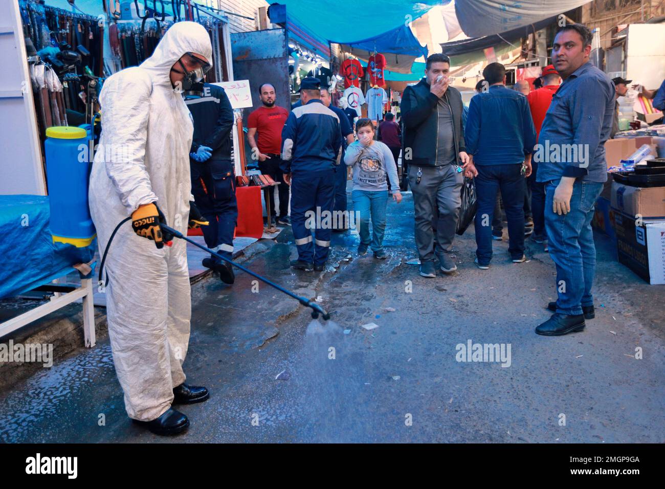 A civil defense worker wearing a protective suit sprays disinfectants ...