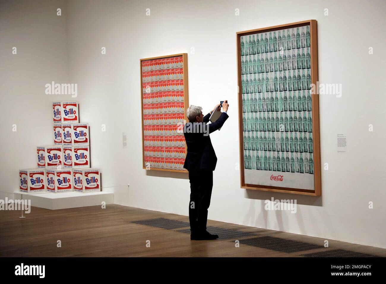 A man takes pictures of the Andy Warhol 1962 piece "Green Coca-Cola ...