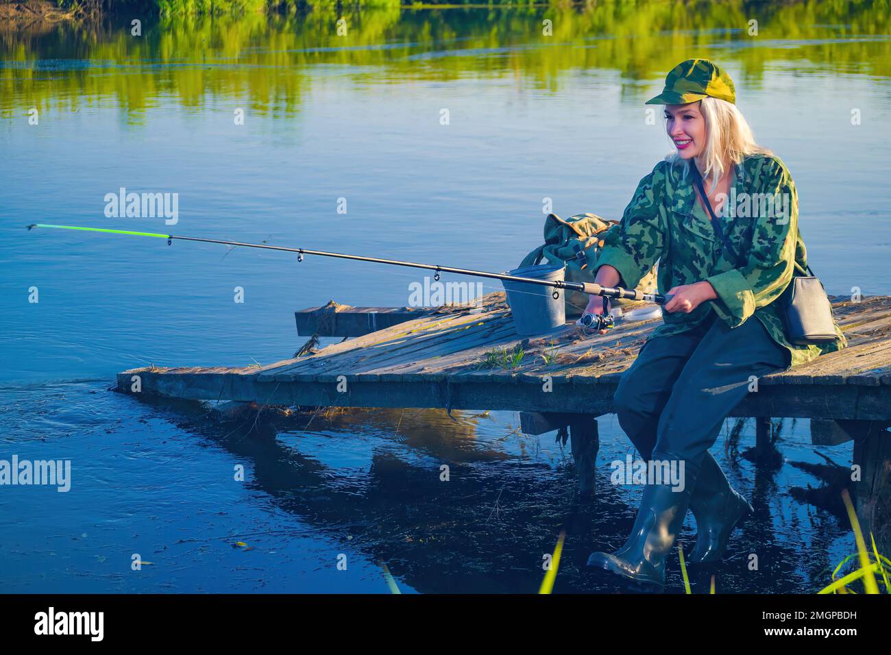 Happy woman on vacation. Fisherman catches and pulls fish on the rod ...