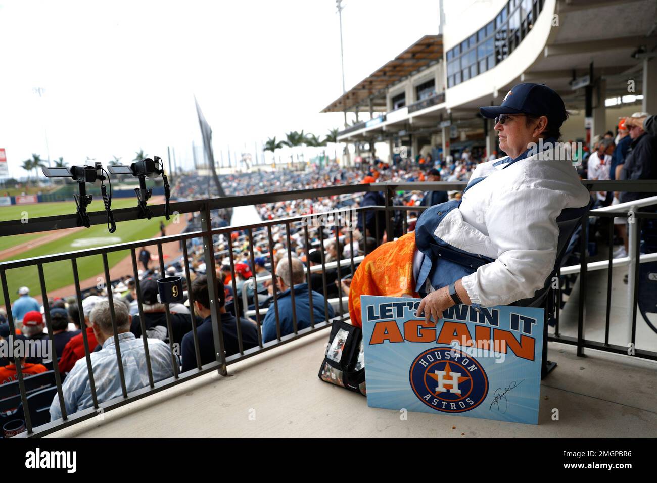 A fan sits with a sign as she watches the fourth inning of a spring ...