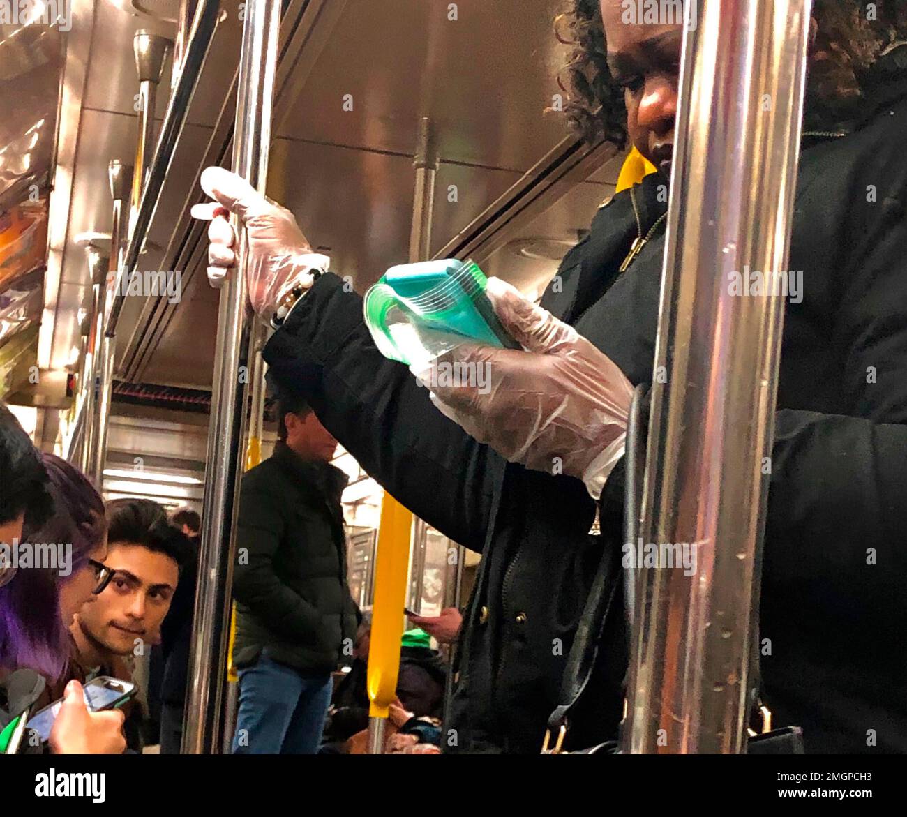 A woman uses protective gloves as she looks at her phone wrapped in a ...