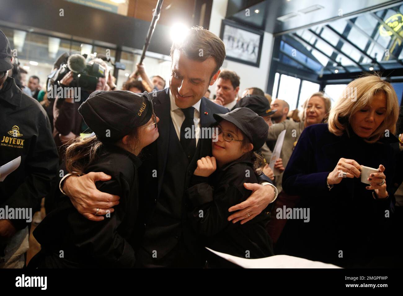 French President Emmanuel Macron hugs two staff members during the ...