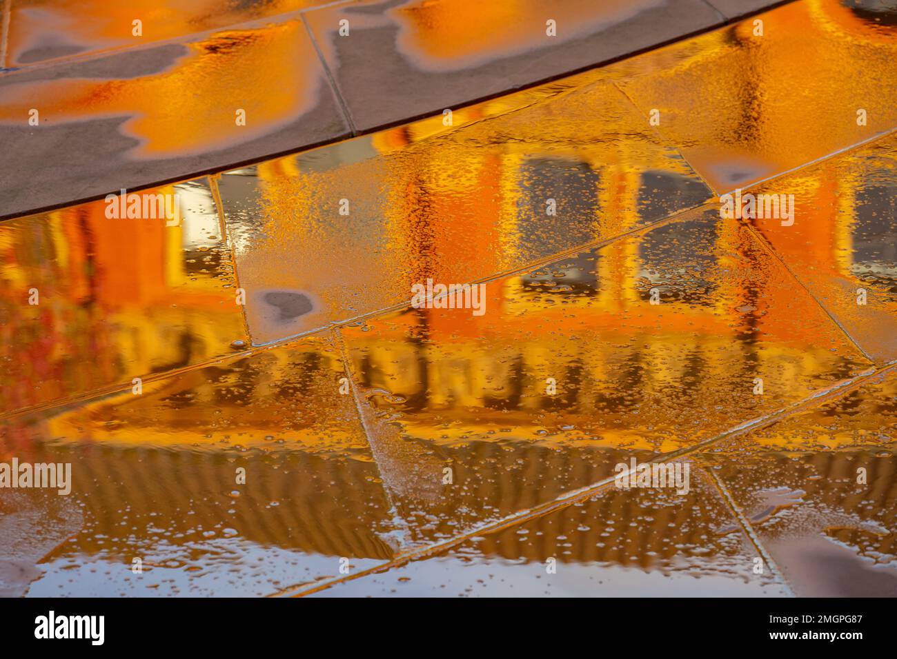 The sunlit wall of the Victoria and Albert museum reflected in wet ...