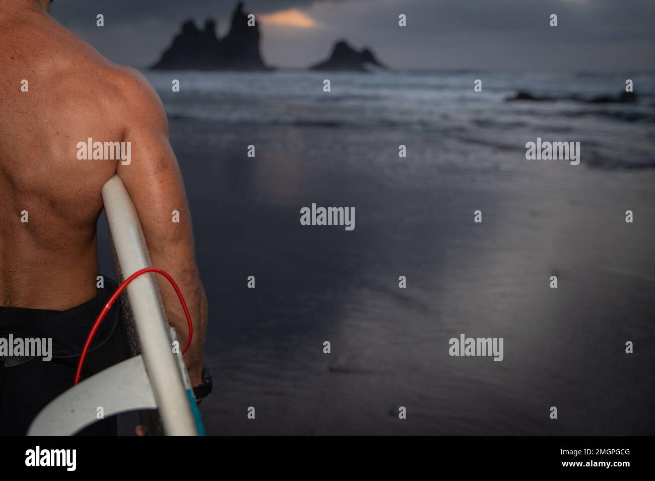 Back view of a surfer holding a surfboard at the beach, copy space on ...