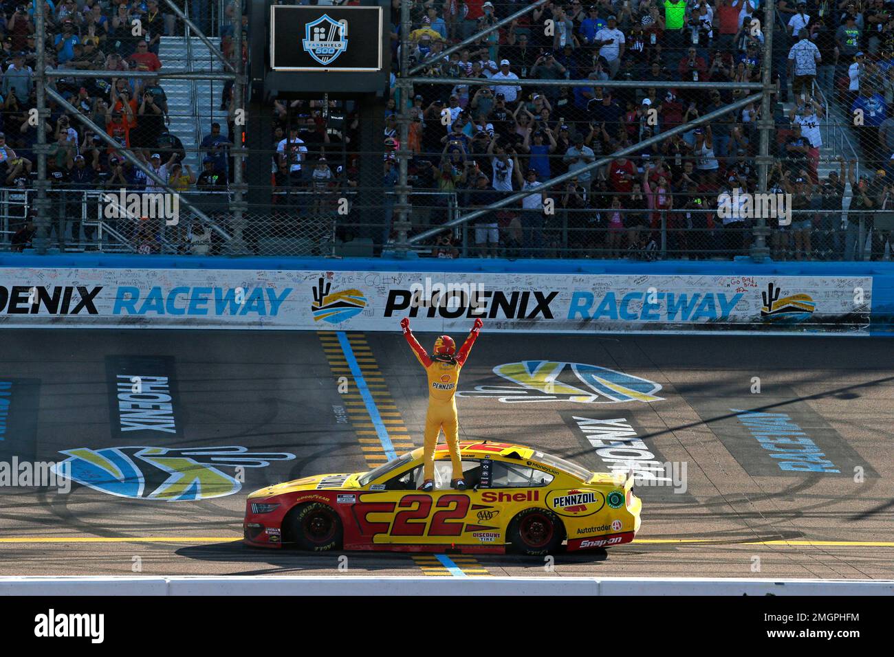Driver Joey Logano stands on his race car at the start-finish line as ...