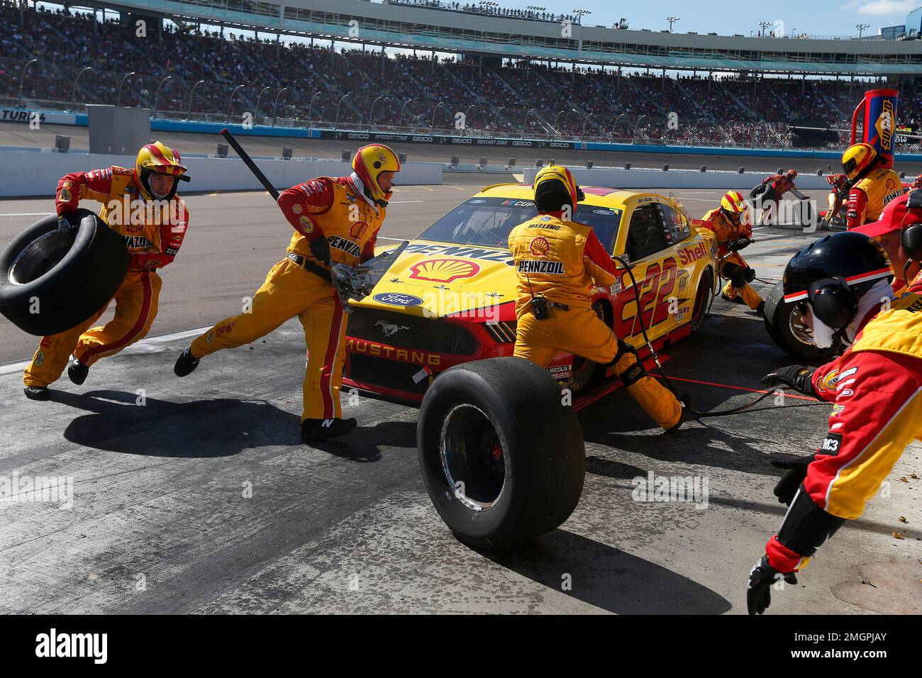 The pit crew for Joey Logano work to change the tires on his car during ...