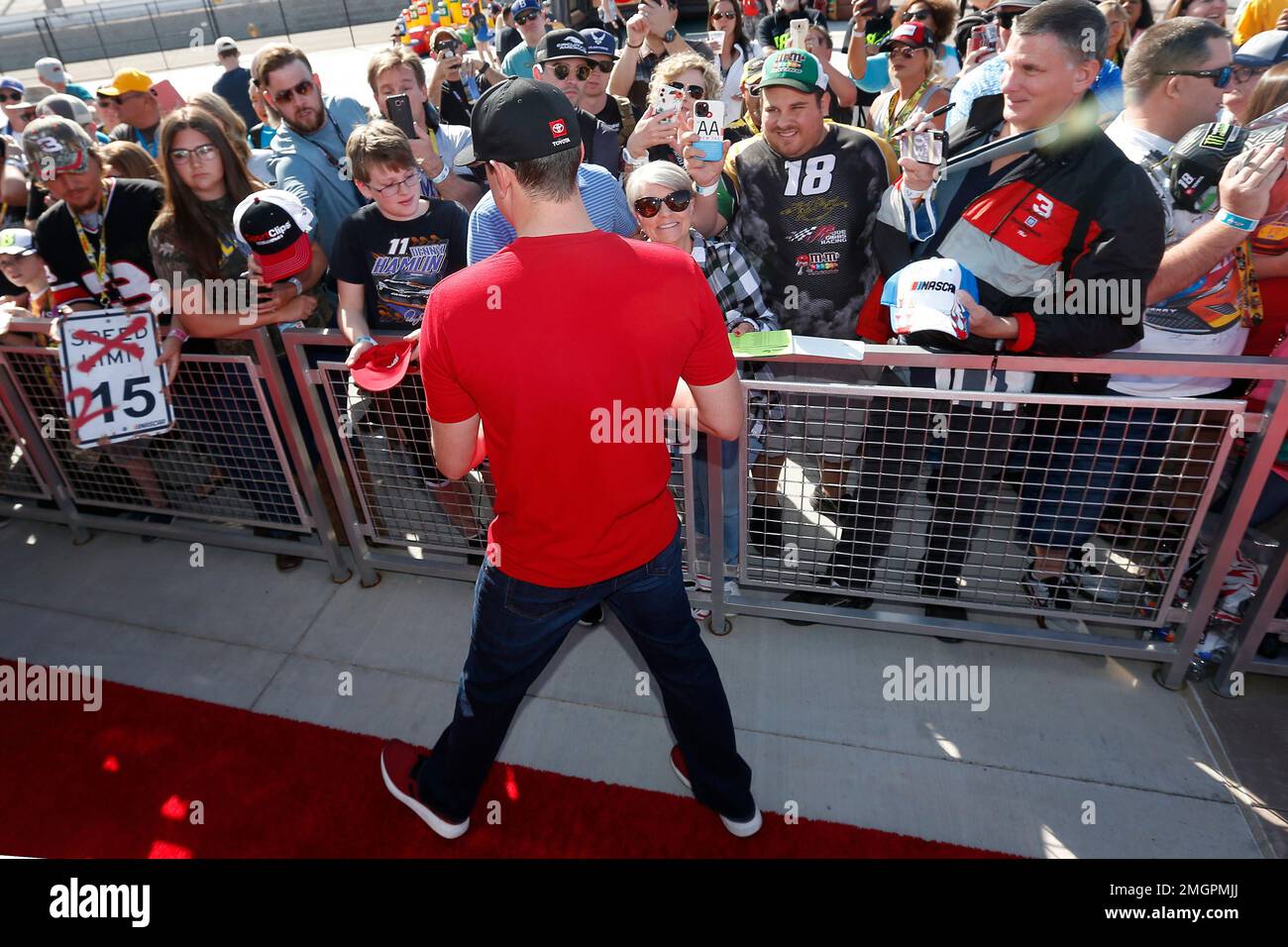 Driver Kyle Busch, front, gives autographs to fans prior to a NASCAR ...