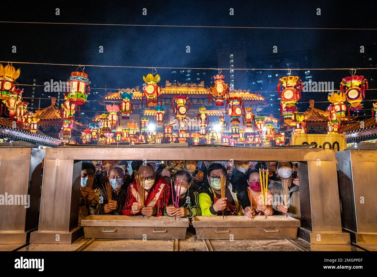 Worshippers wait at the incense burner to burn their first joss sticks ...