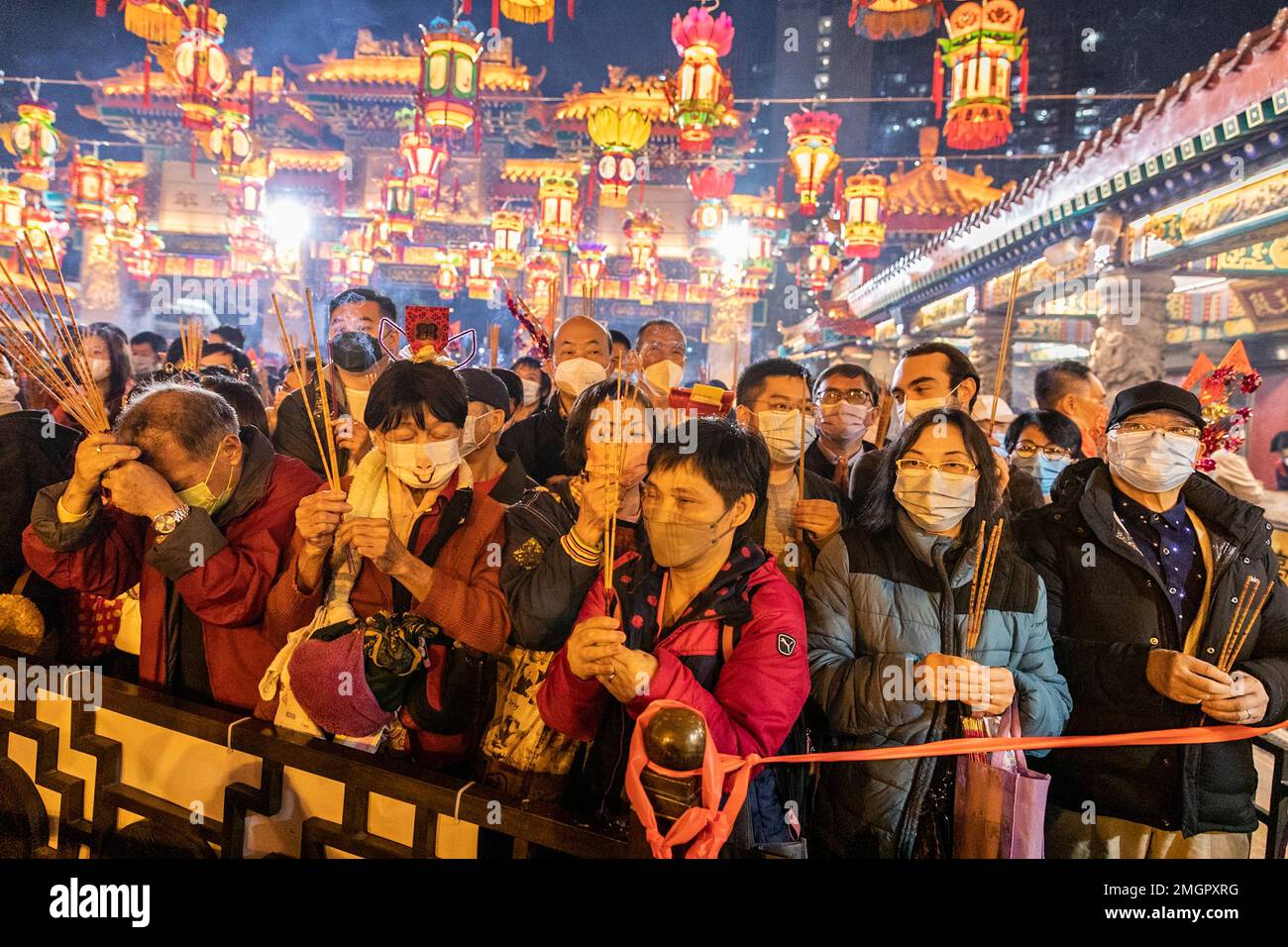 Worshippers wait in line for their first joss sticks to be burned at ...