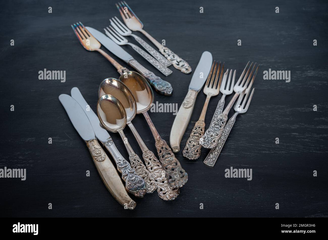 An assortment of silver forks, spoons, and knives with intricate ...