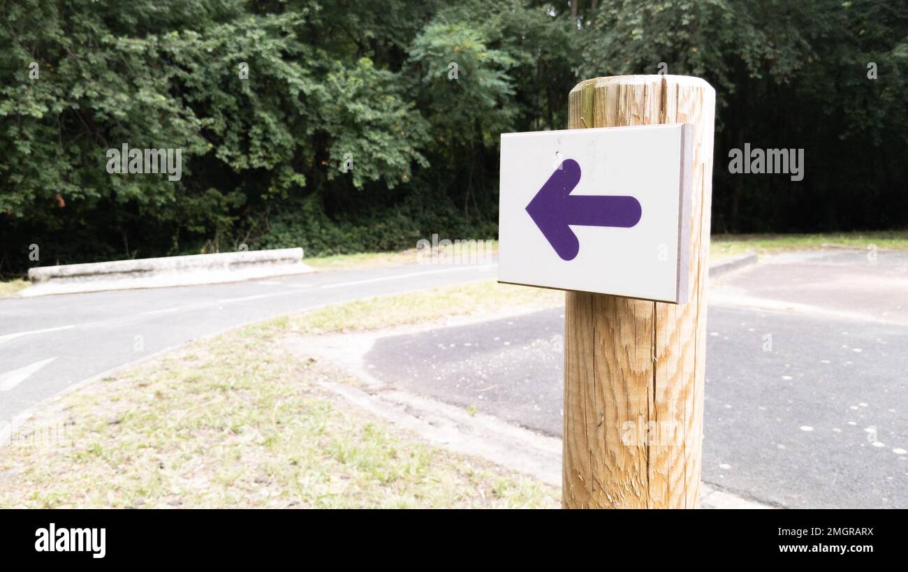 wooden arrow purple pointing the direction of footpath for hike trail ...