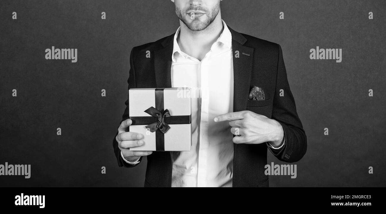 cropped man point finger on wrapped box on black background, boxing day ...