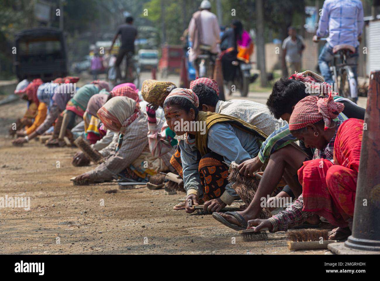 Indian laborers work to manually repair a road on the outskirts of ...