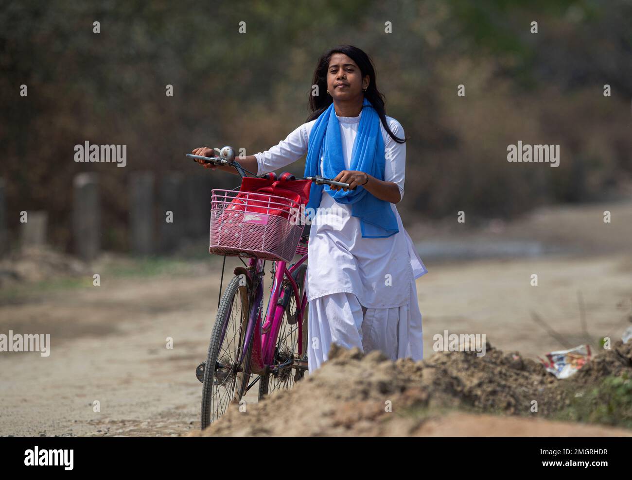 An Indian girl pushes her bicycle home from college, on the outskirts of Gauhati, India ...