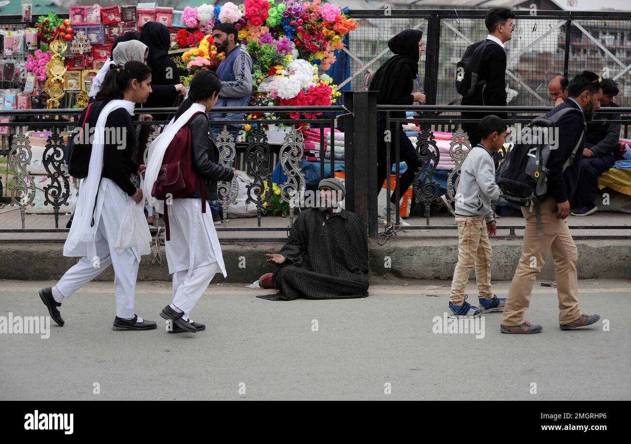 An elderly Kashmiri man asks for alms as people walk past in Srinagar ...