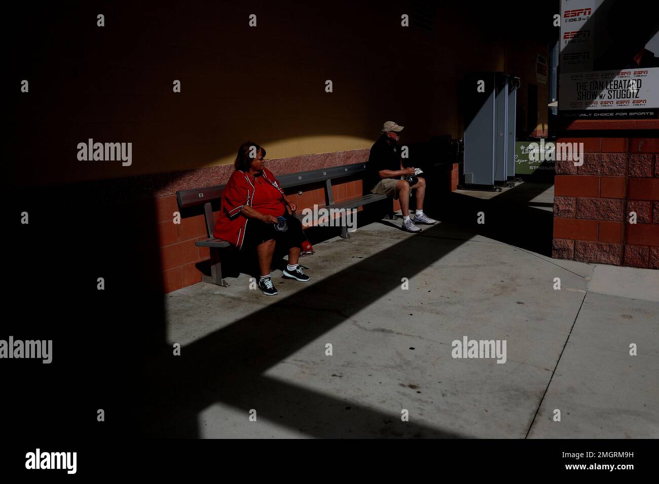 Fans rest on a bench during the sixth inning of a spring training ...