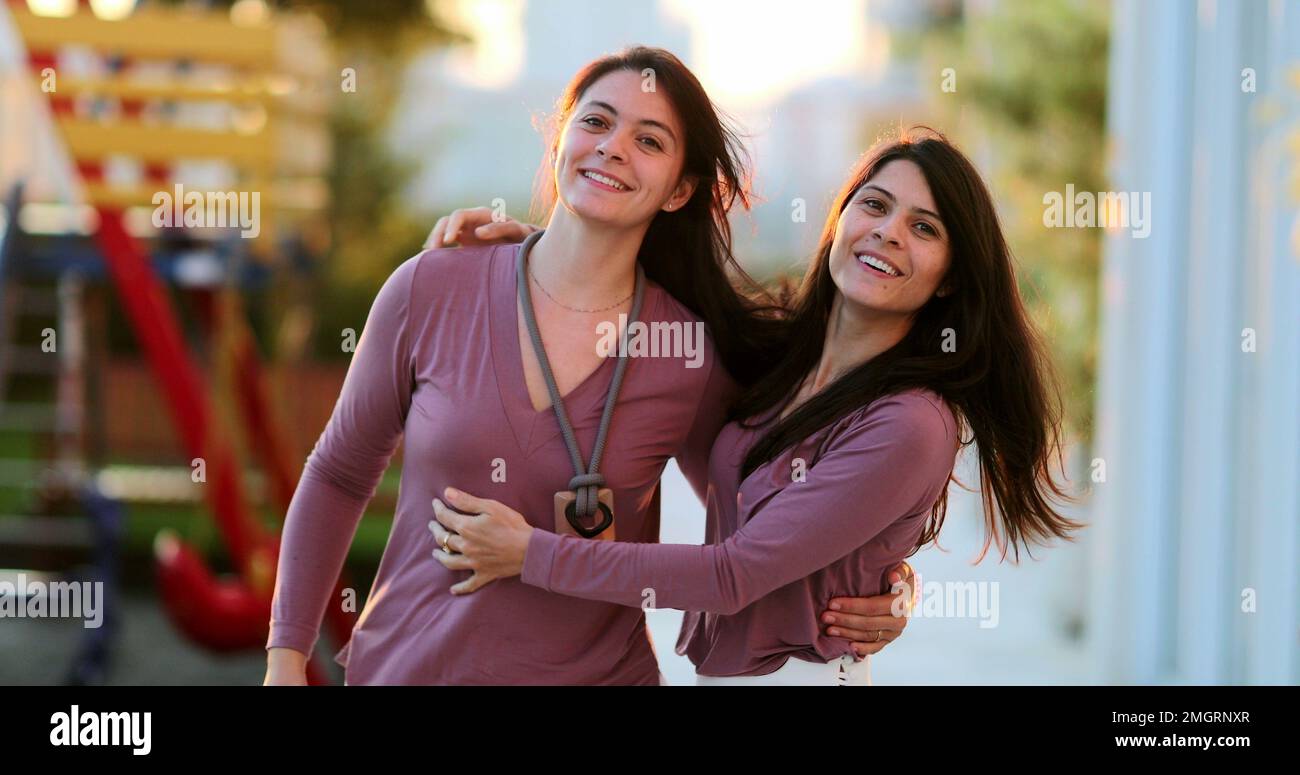 Two adult happy sisters posing together outside twin siblings with same ...