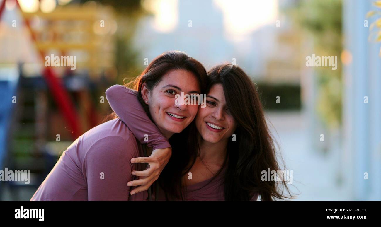 Two adult happy sisters posing together outside twin siblings with same ...