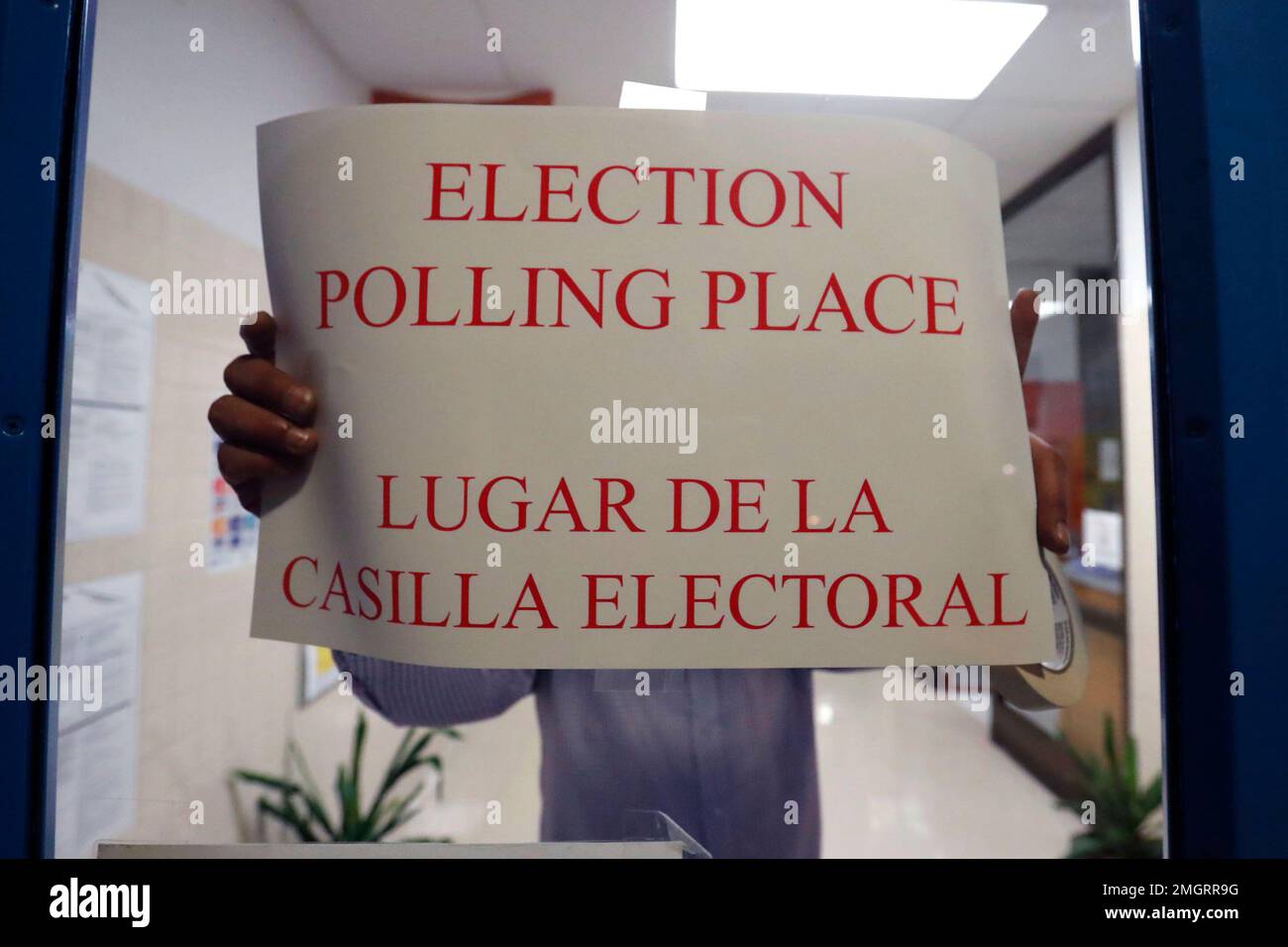 Dallas County election worker Maxx Nunez tapes up a sign on a window ...