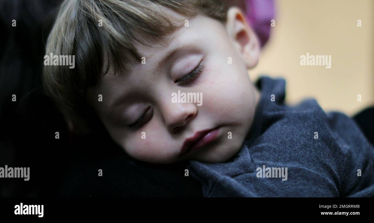 Tired little boy sleeping on parent arms closeup child face asleep ...